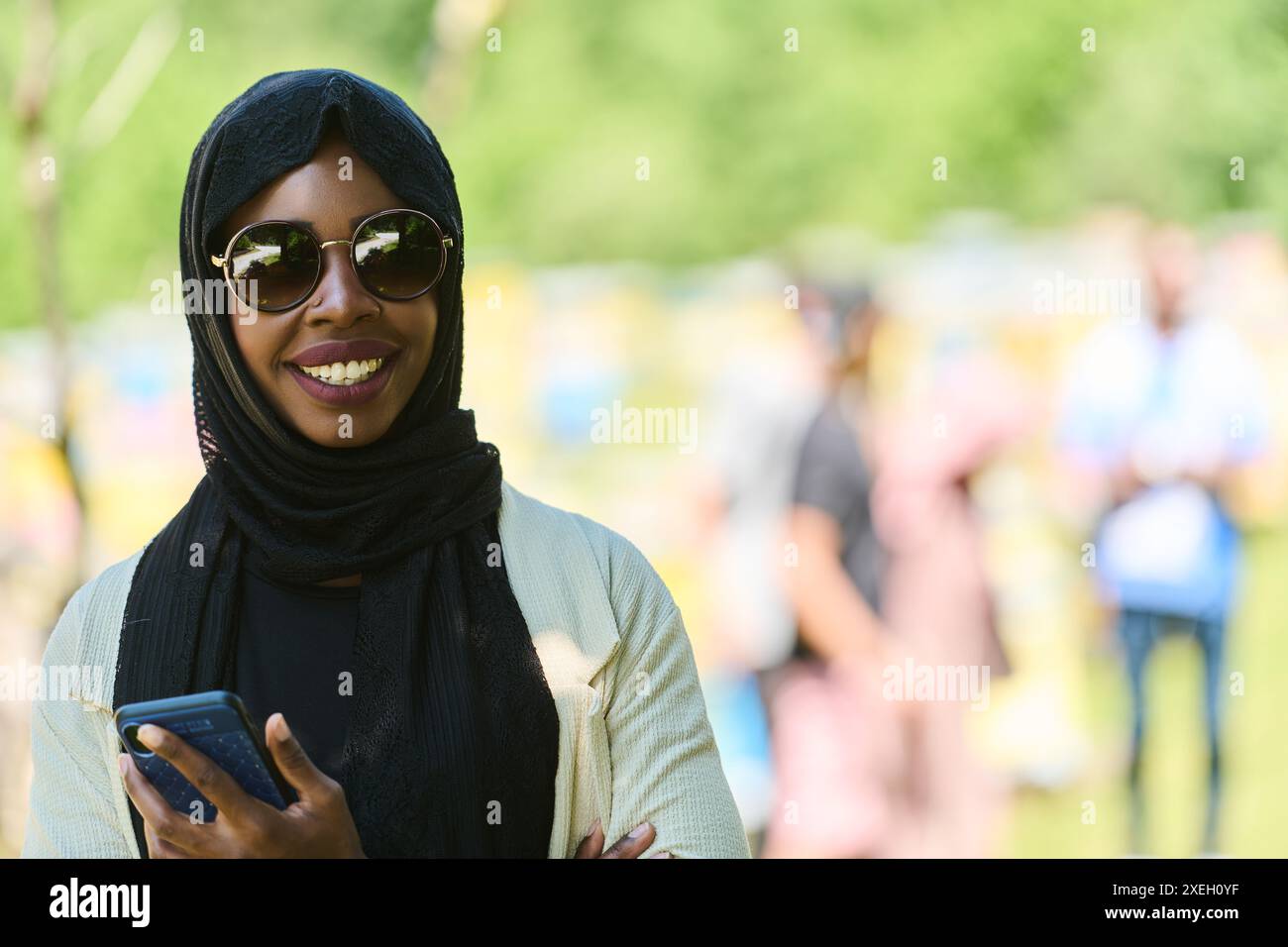 Middle Eastern Muslim woman in a hijab uses a smartphone while managing ...