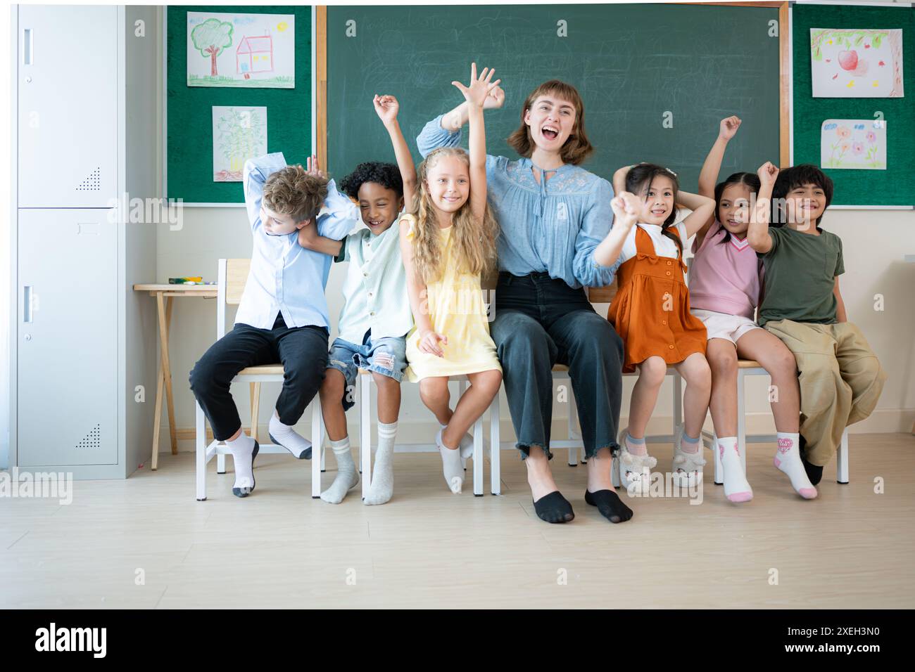 Portrait of a teacher and kids in a classroom where children have pleasure learning Stock Photo ...