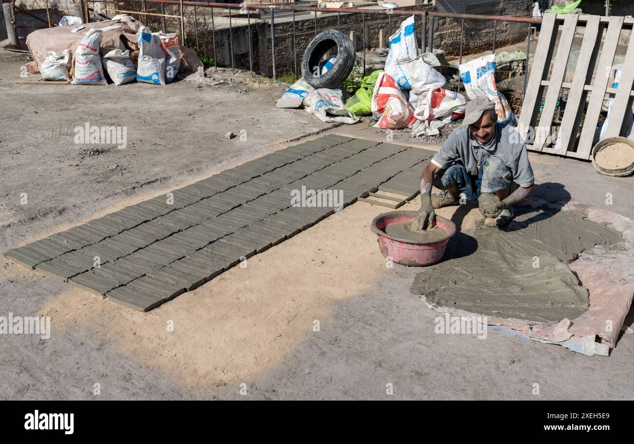 Labourer making clay and cement bricks in the traditional way in a ...