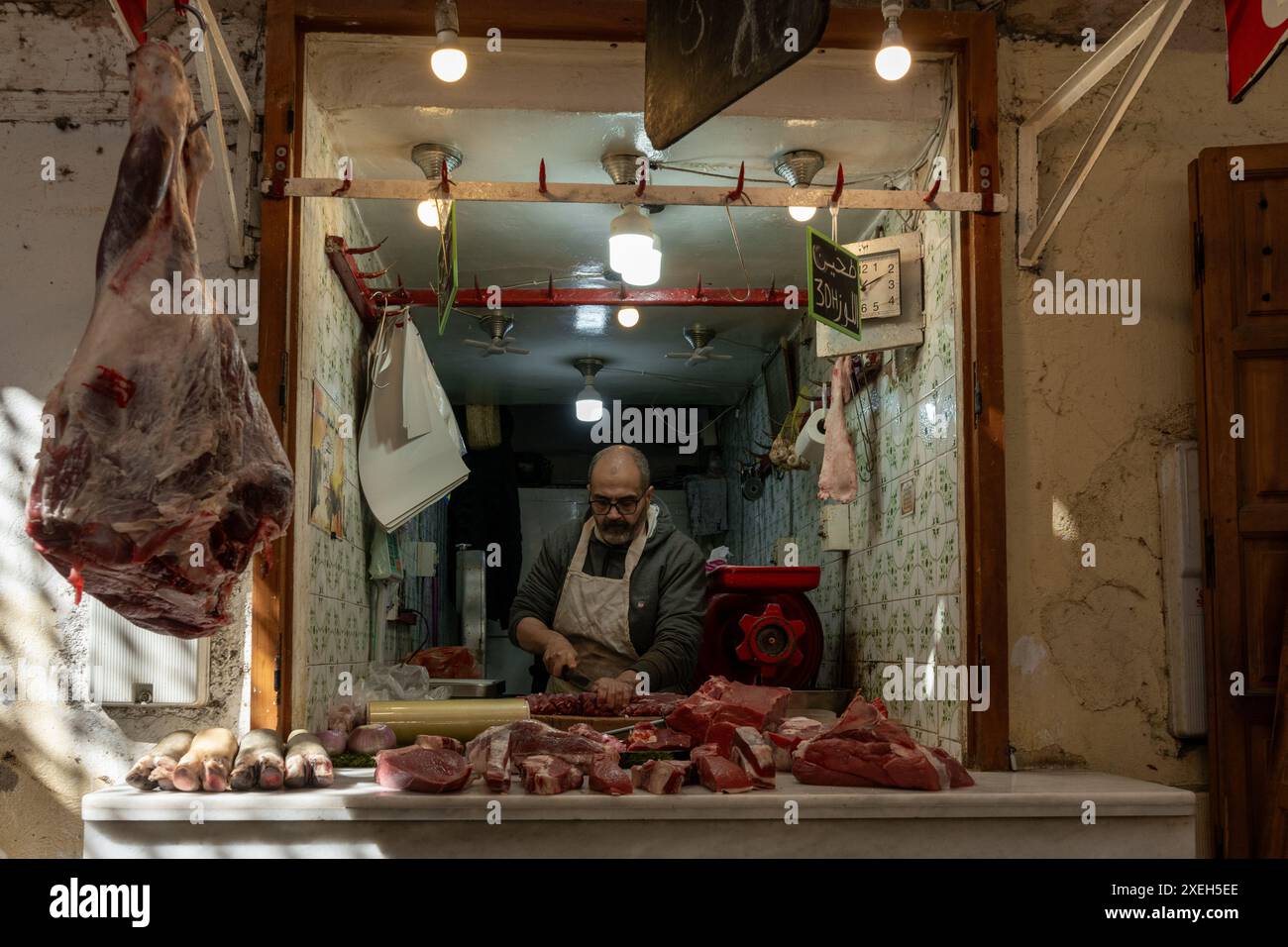 Butcher preparing fresh cuts of meat in his market stall in the souk of ...