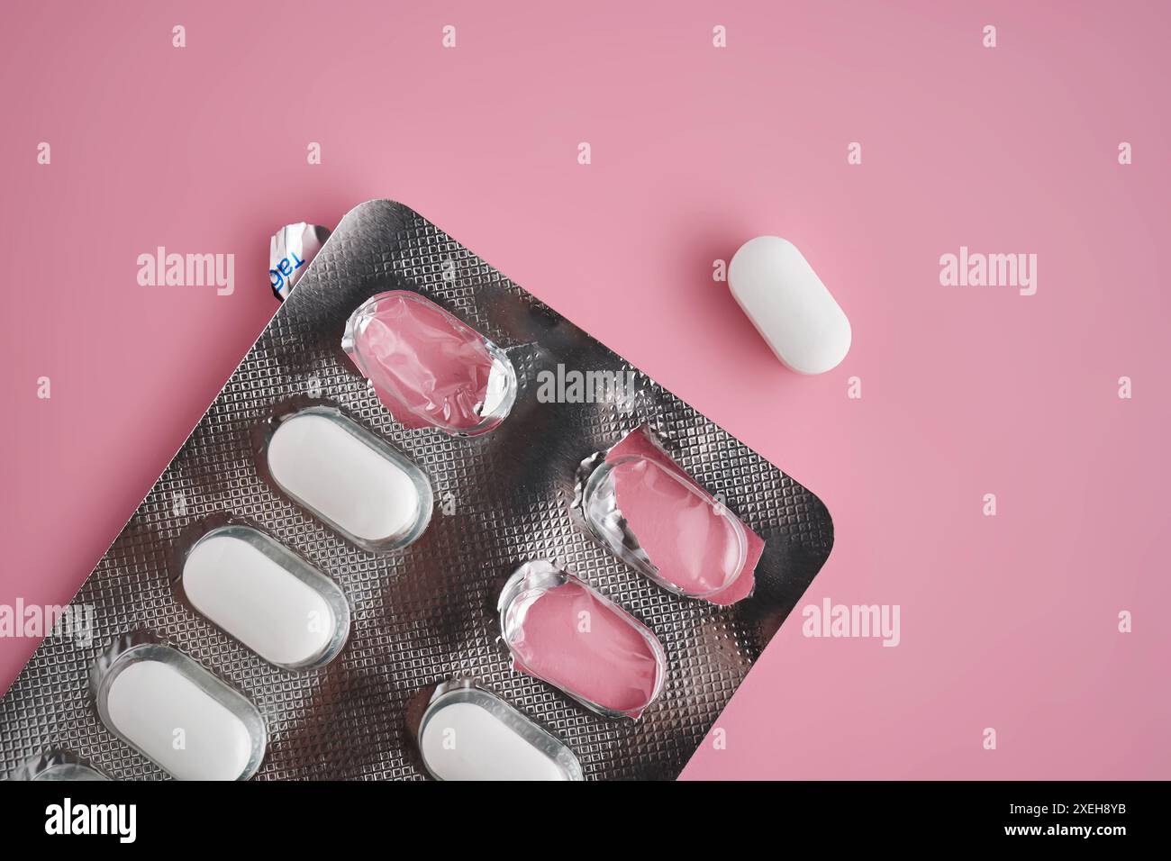 Open pack of pills on a pink background Stock Photo - Alamy