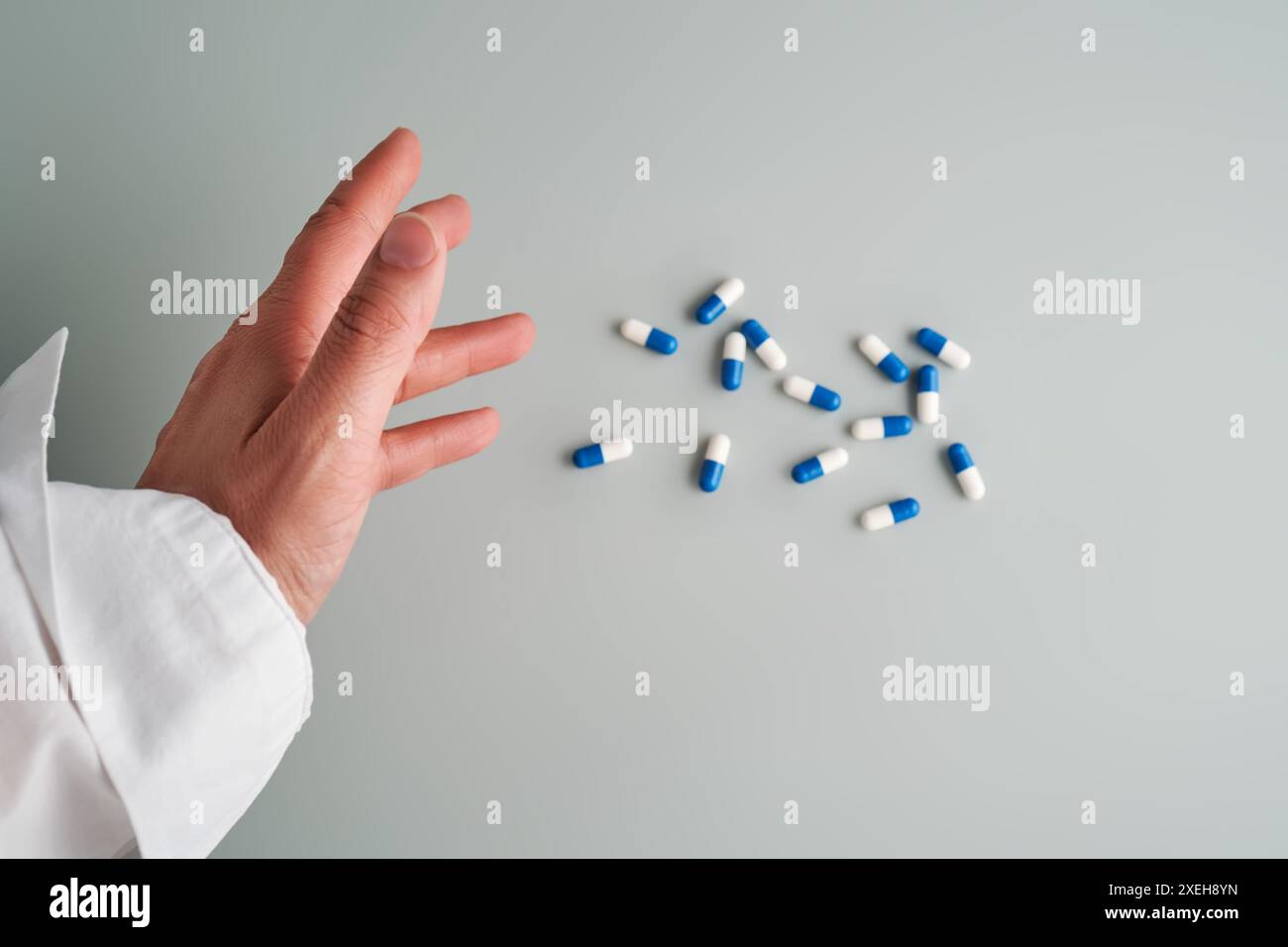 Hand reaches out to a white and blue pill on a blue background Stock ...