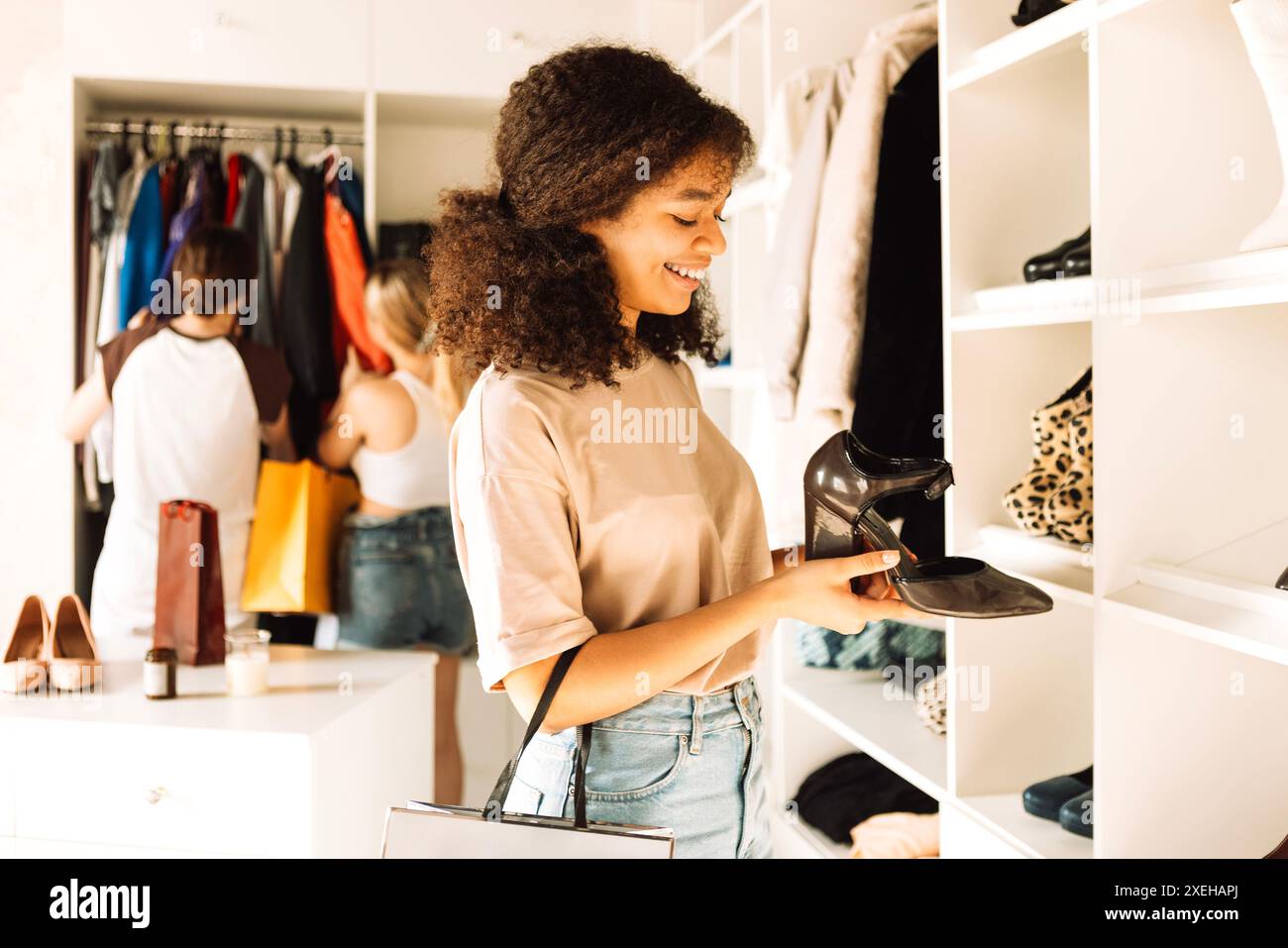 Charming teenage girls of different races choose clothes and shoes in ...
