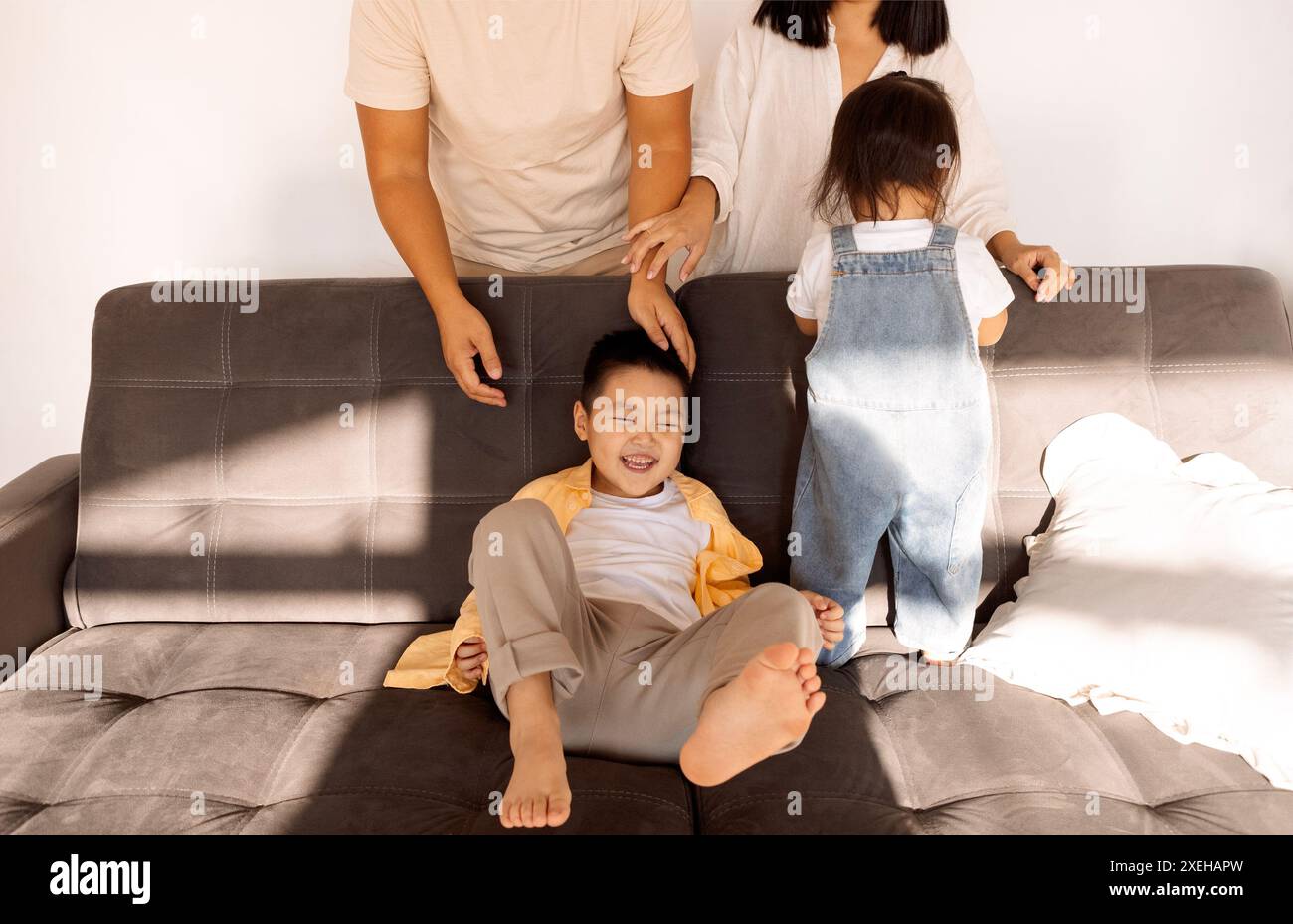 A Korean couple and their cute little kids on the sofa in the living ...