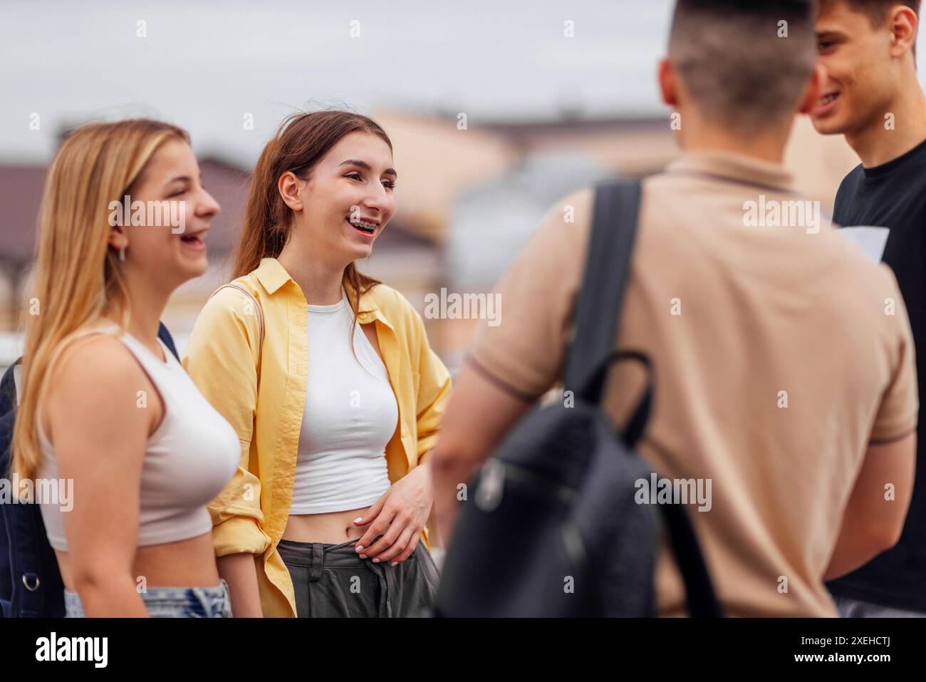 Four teenagers in casual clothes chat and laugh on the roof of the ...