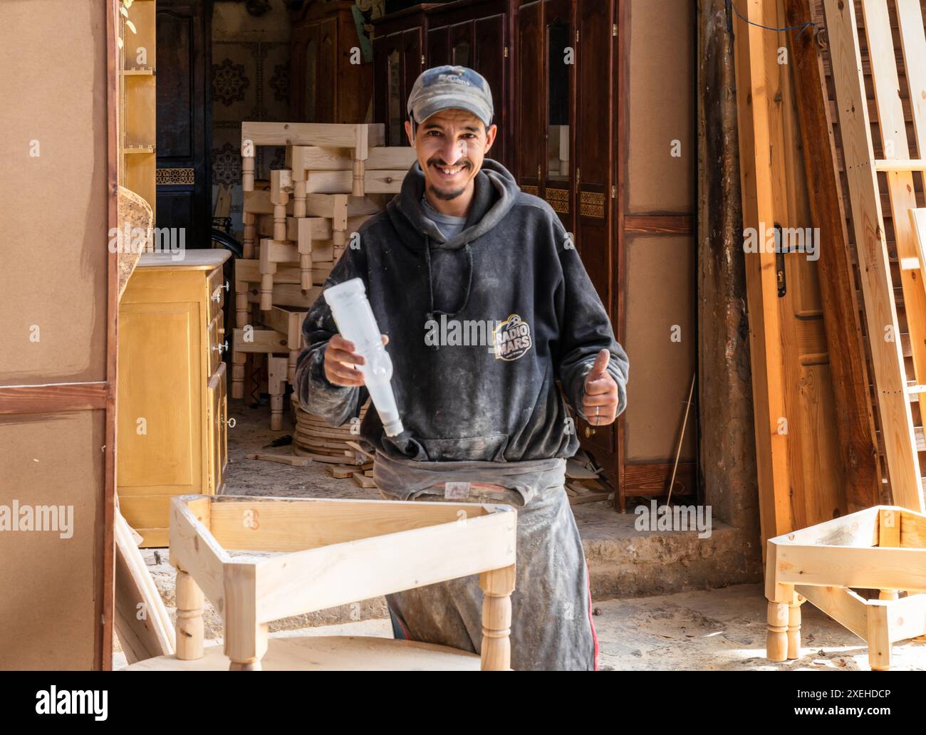 Young carpenter smiling with pride and working in his woodworkshop and ...