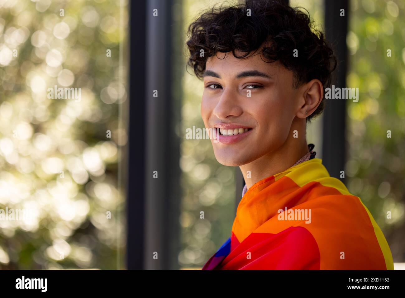Smiling transgender woman wrapped in rainbow flag, celebrating LGBTQ+ ...