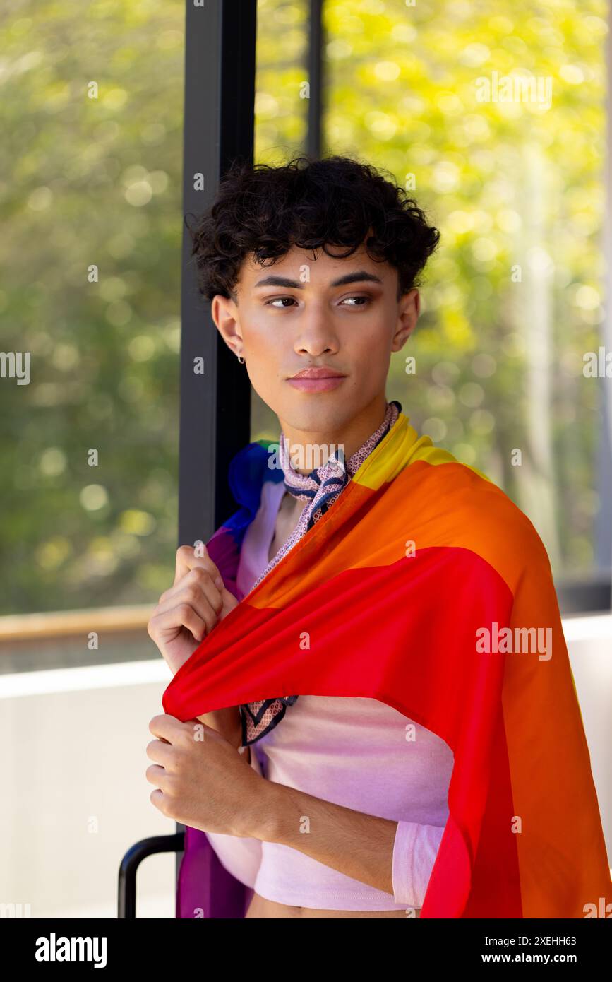 Wearing rainbow flag, transgender transgender woman standing by window ...