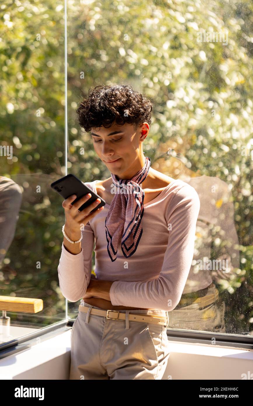 Using smartphone in school, transgender woman standing by window ...