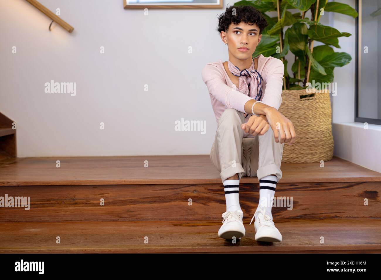 Sitting on wooden stairs, transgender woman looking thoughtful in ...