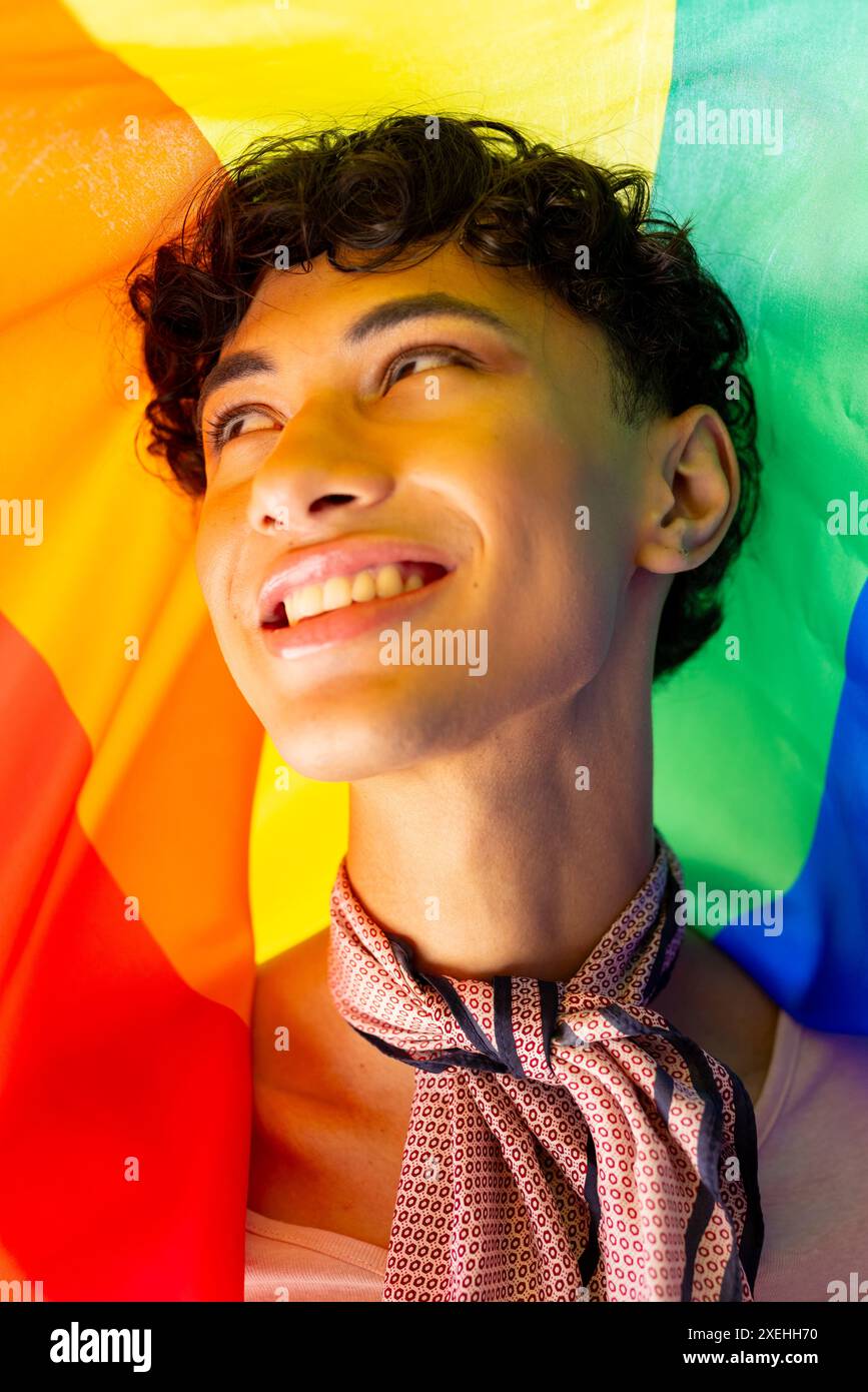 Smiling young man wrapped in rainbow flag, celebrating LGBTQ+ pride and ...