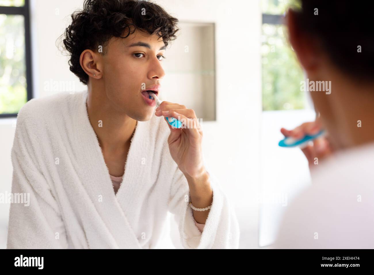 Brushing teeth in bathroom, young young man in bathrobe looking in ...