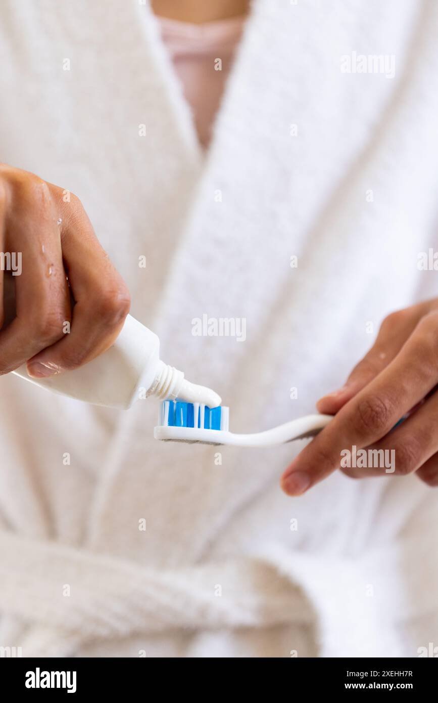 Applying toothpaste on toothbrush, young man in bathrobe preparing for ...