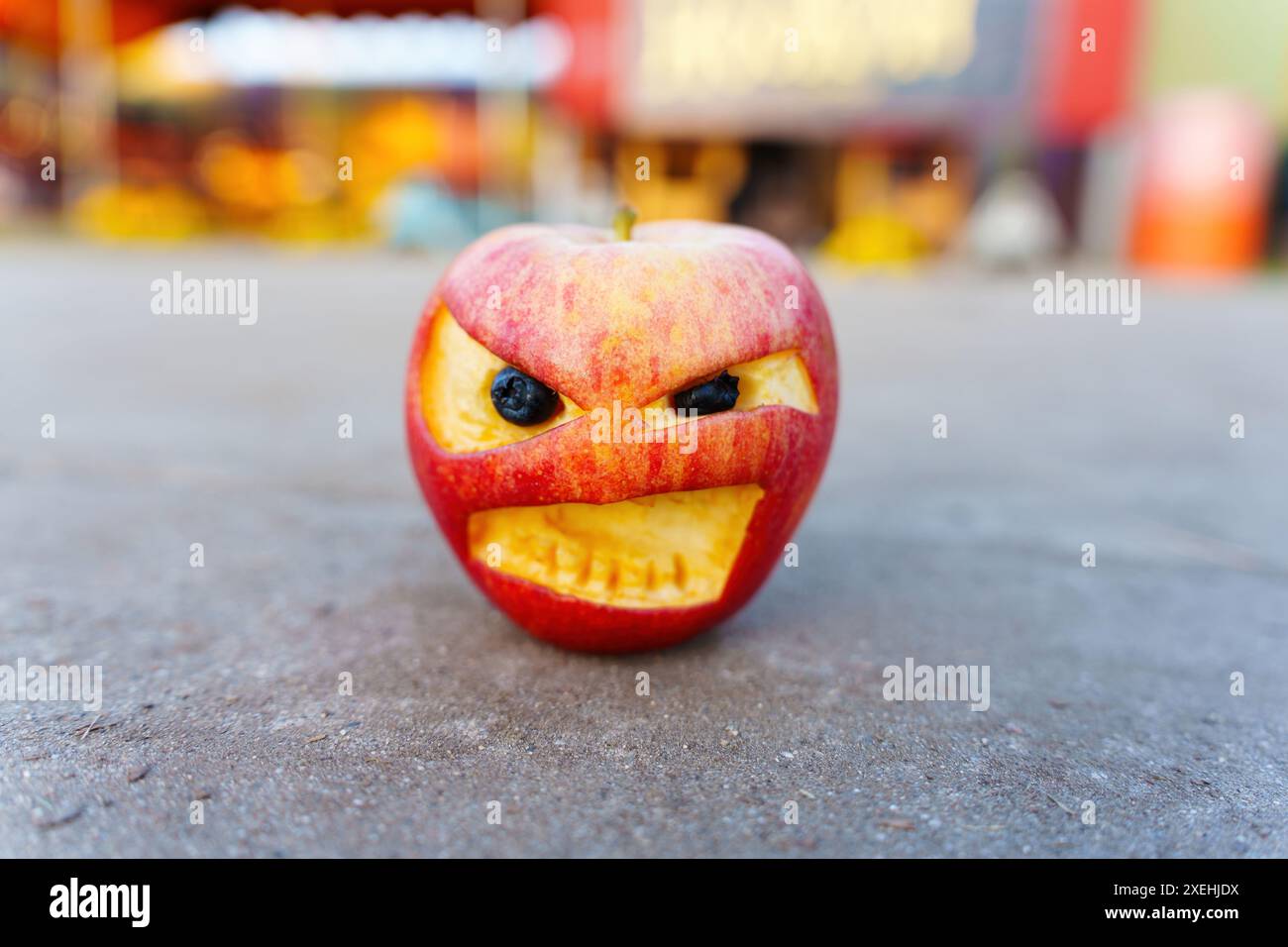 Red apple intricately carved with an angry face expression, set on a ...