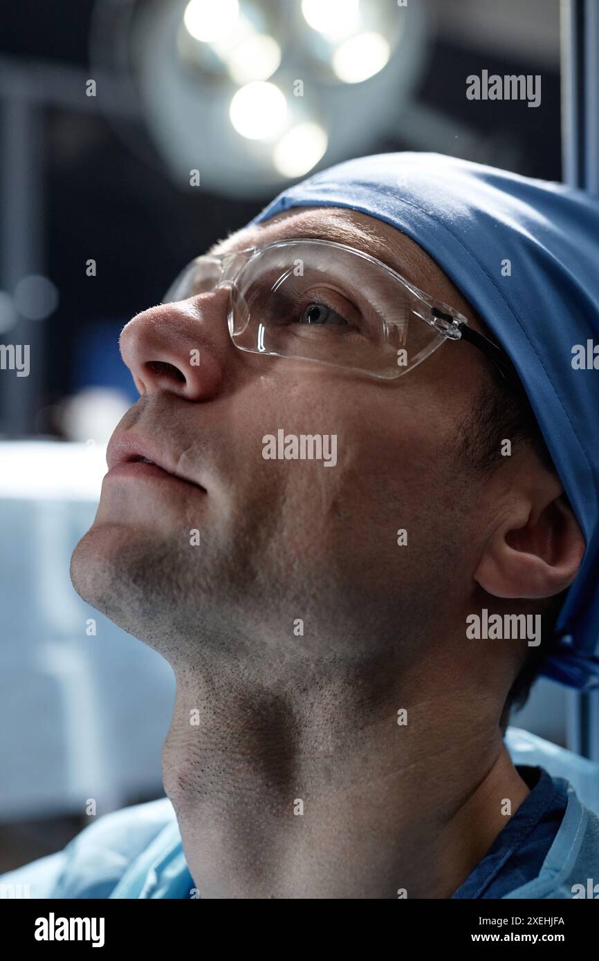 Vertical side view portrait of male surgeon looking up in operating ...