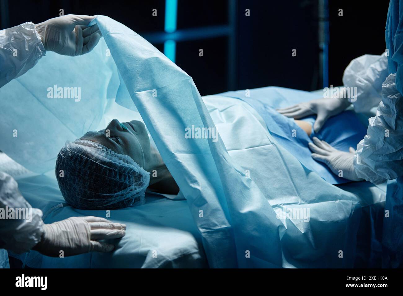 Adult woman covered by drapes lying on operating table preparing for ...