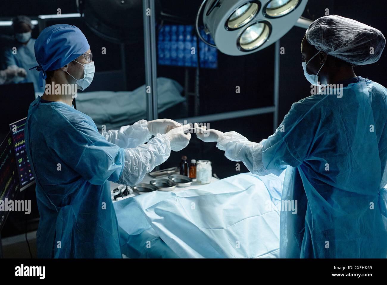 Side view portrait of medical assistant handing tools to surgeon ...