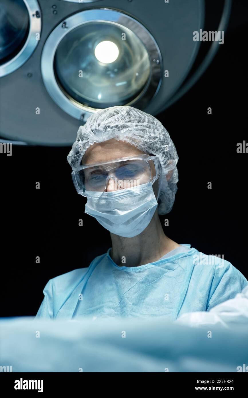 Vertical portrait of mature female surgeon wearing mask performing ...
