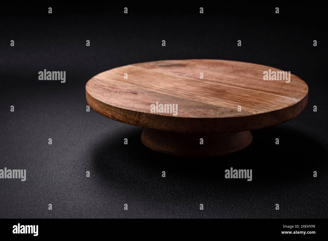 Beautiful round wooden cake stand on a textured concrete background ...