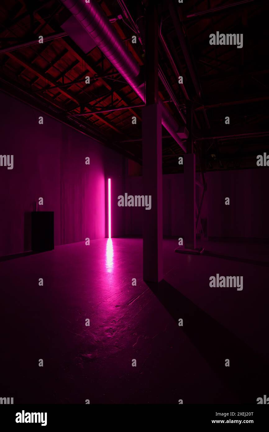 A modern art exhibit with colorful neon lights in a dark warehouse ...