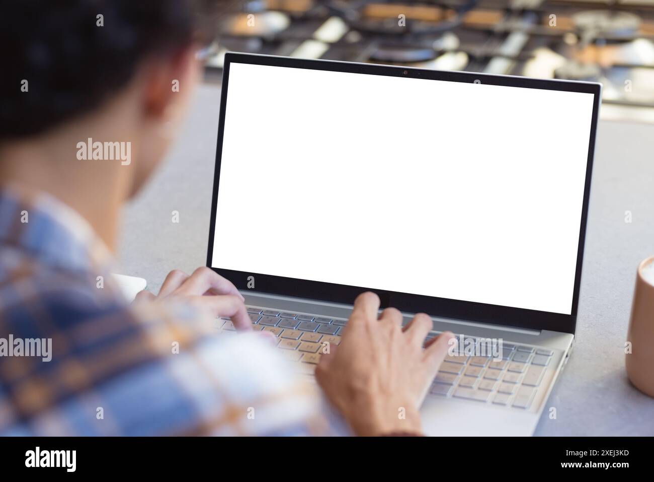 Using laptop with blank screen, teenage boy typing at home with coffee ...