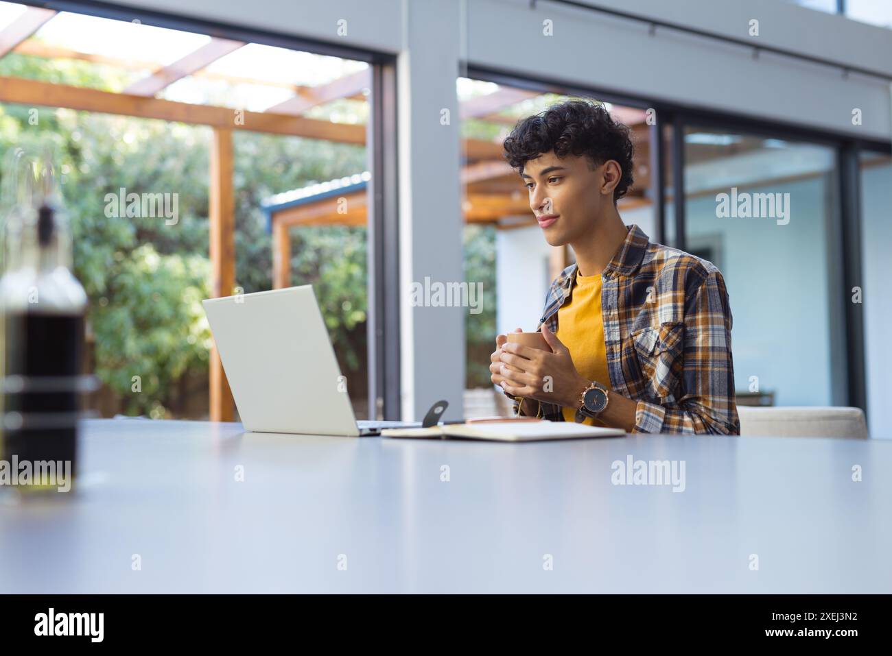 Using laptop, teenage boy with notebook studying at home, focusing on ...