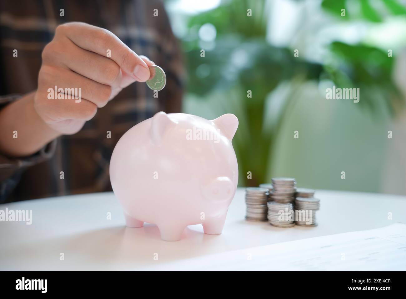 Saving money. hand putting money into pink piggy bank making ...