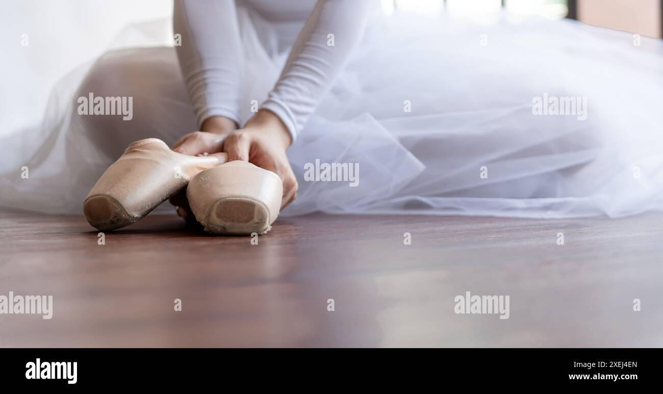 Ballerina in ballet shoes. Asian girlÂ tying ribbons of toe shoes ...