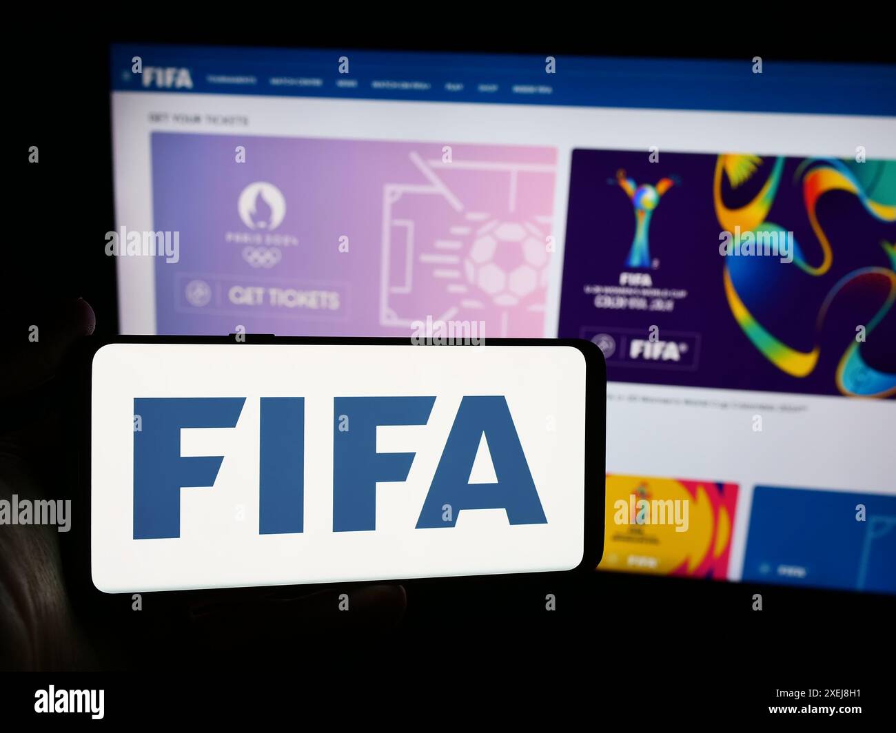 Person holding mobile phone with logo of Federation Internationale de ...