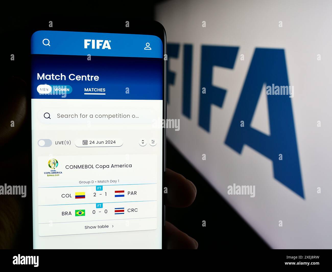 Person holding mobile phone with web page of Federation Internationale ...
