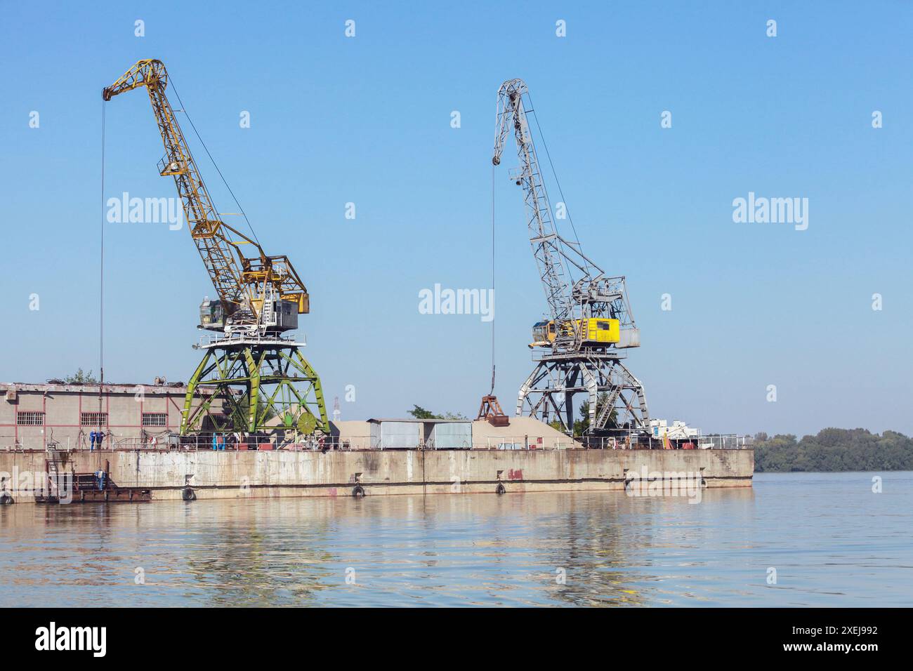 Yellow green portal cranes stand on a quay in harbor of Ruse Port ...
