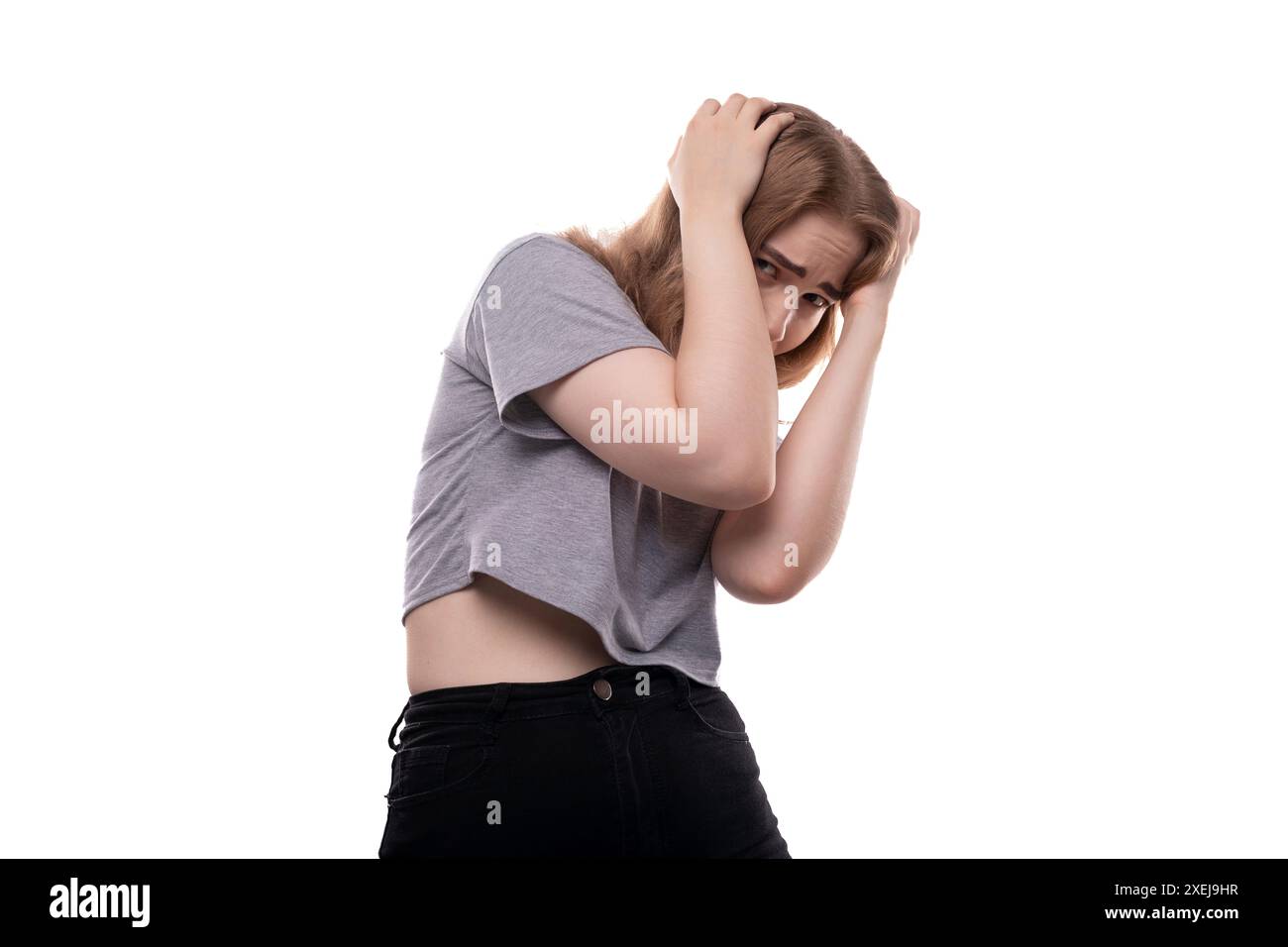 Fearful teenage girl with blond hair in a T-shirt on a white background ...
