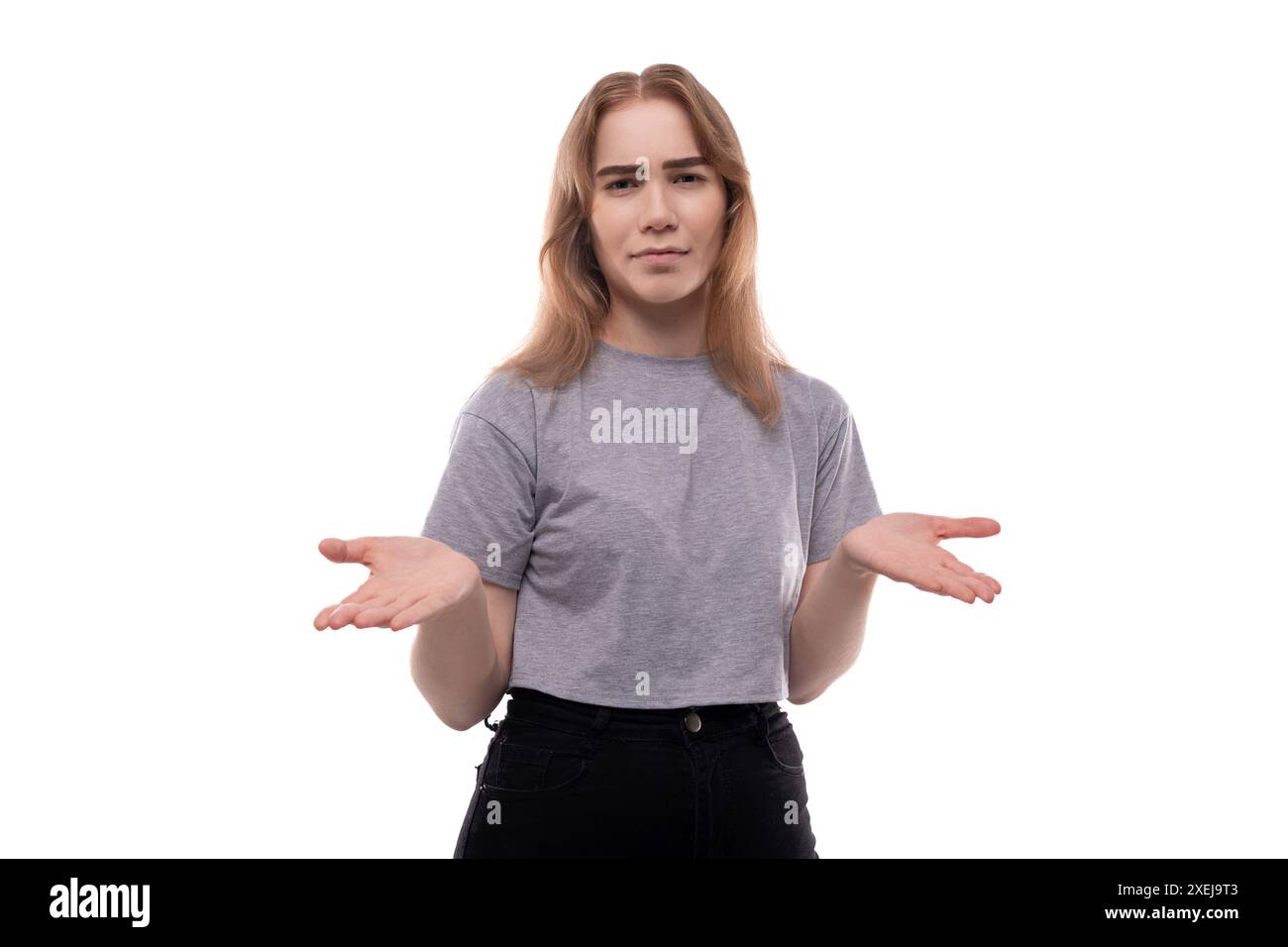 Puzzled bright blonde teenager girl with braces in a gray T-shirt is ...