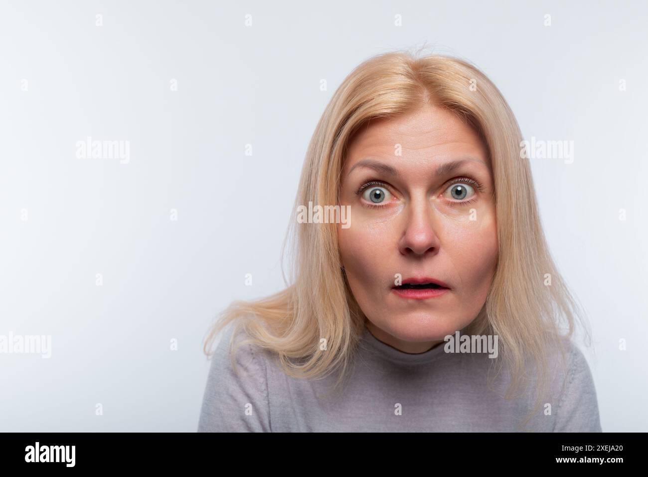 A middle-aged woman with blond hair is surprised and her eyes bulging ...