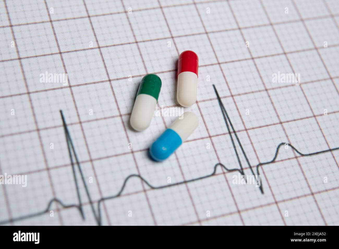 A close-up of three pills in different colors on electrocardiogram (ECG ...