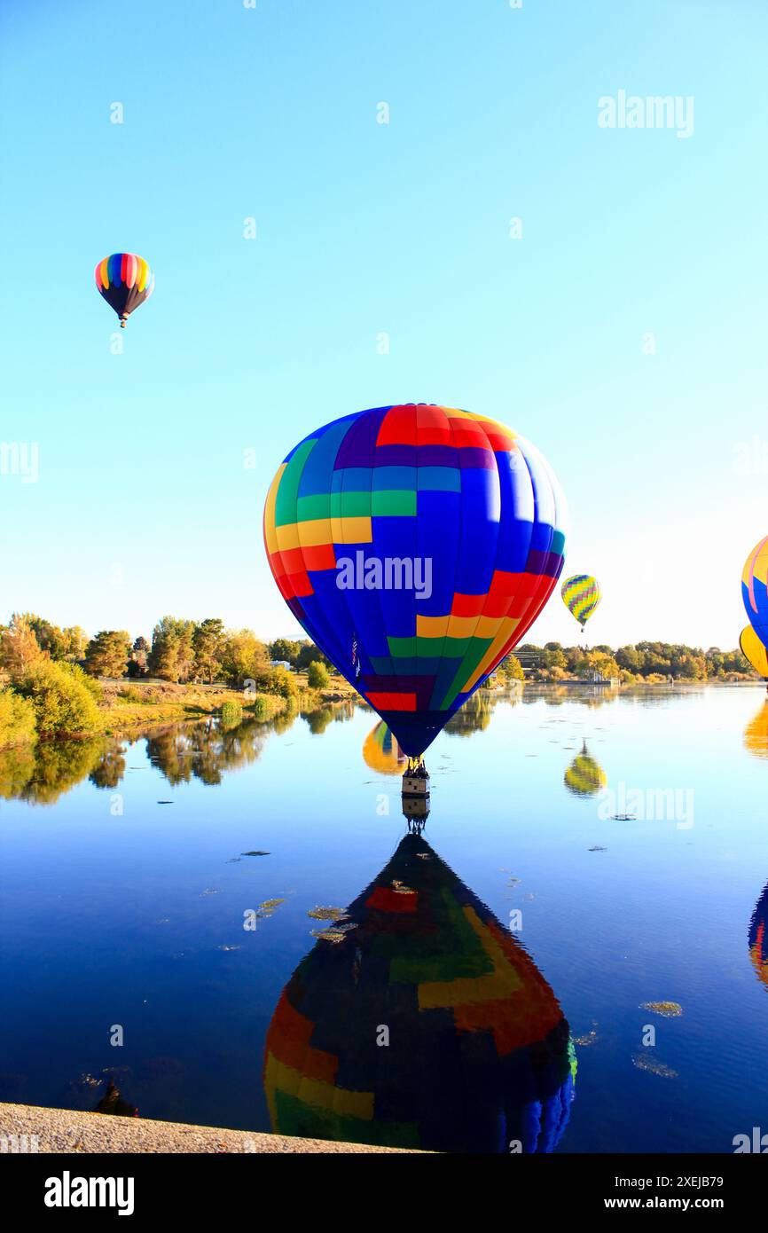 Dawn ascent of vibrant balloons over water Stock Photo - Alamy