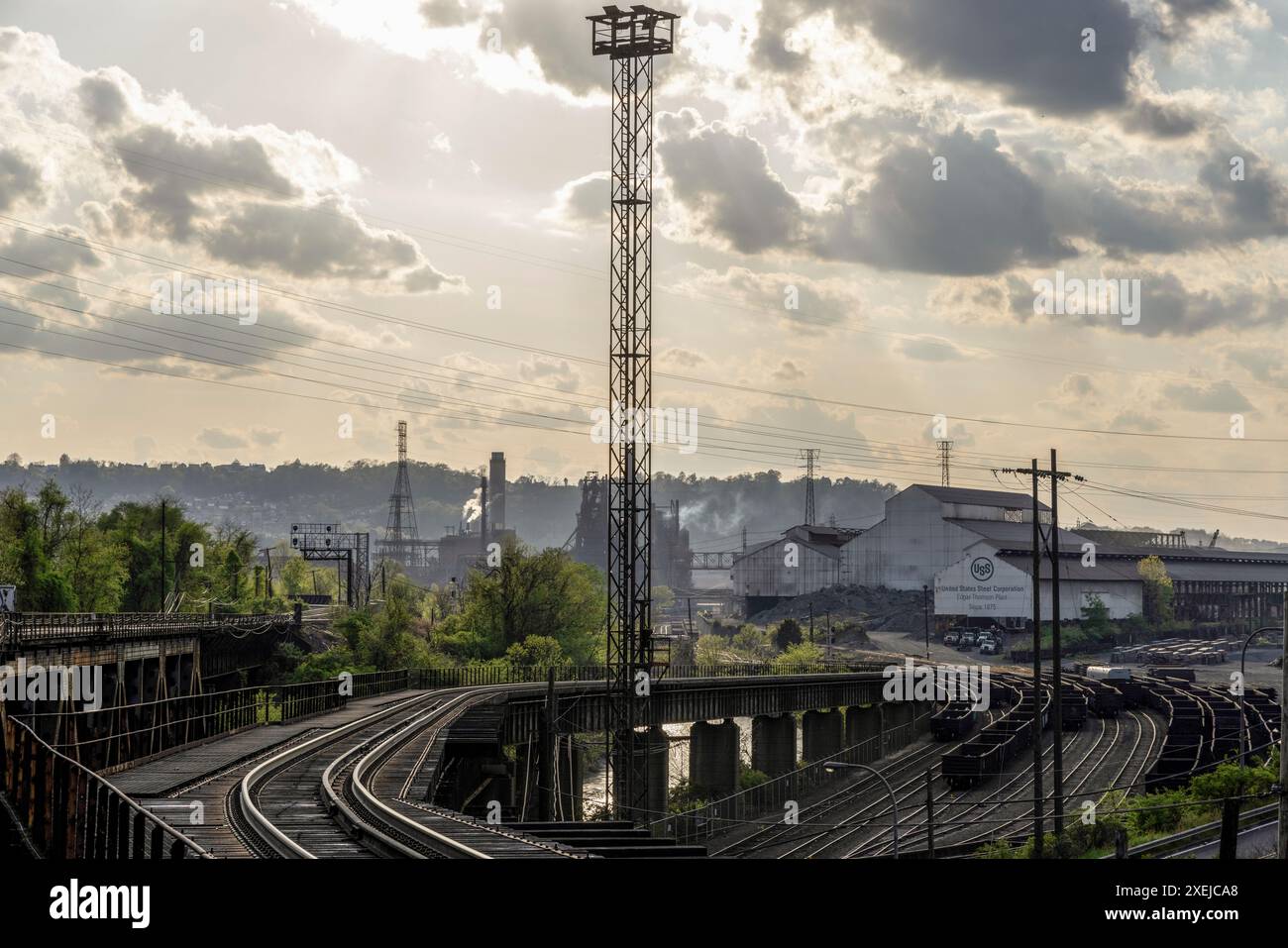 Train tracks leading to a steel mill under cloudy sky Stock Photo - Alamy