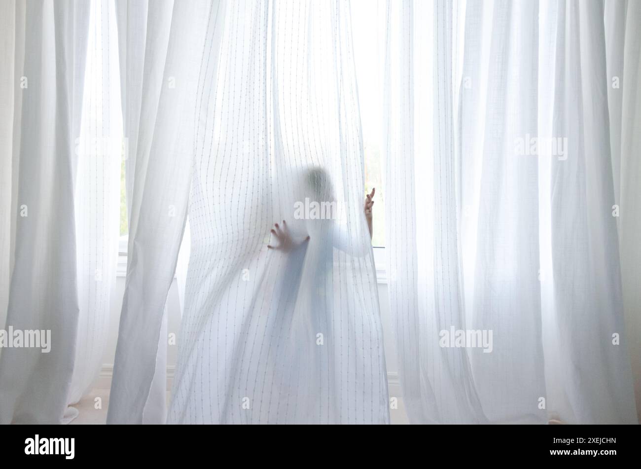 child playing behind sheer white curtains, partially visible Stock ...