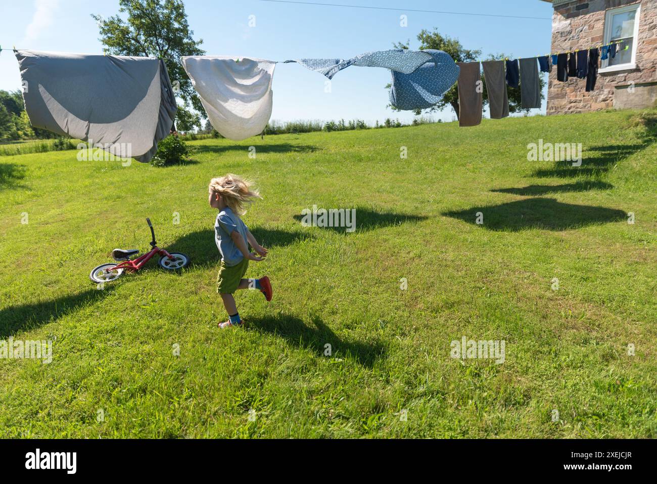A child running on a lawn with a bike and laundry hanging to dry Stock ...