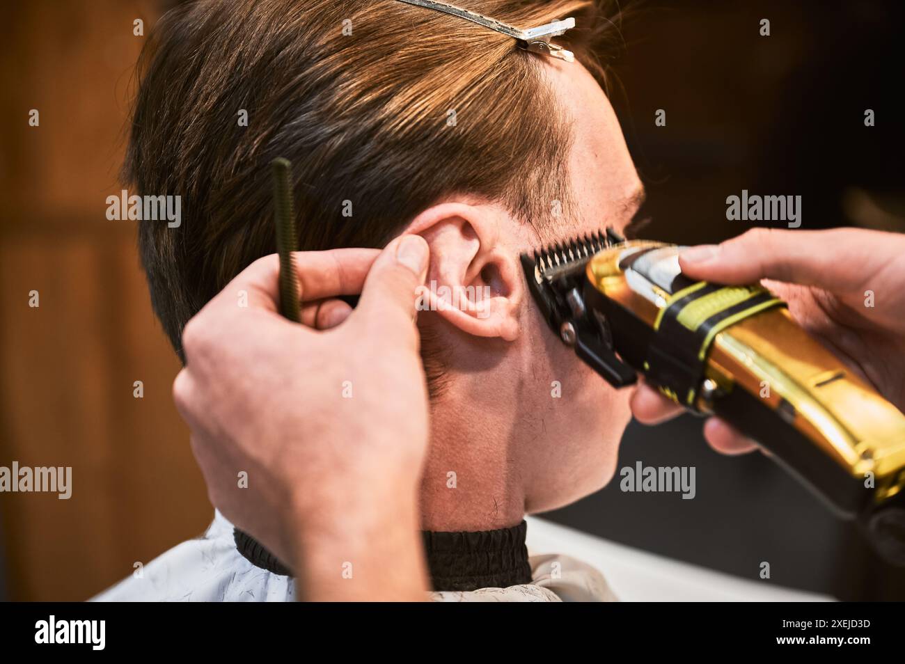 Close-up photo of professional barber shaving sideburns. Holding ear to ...