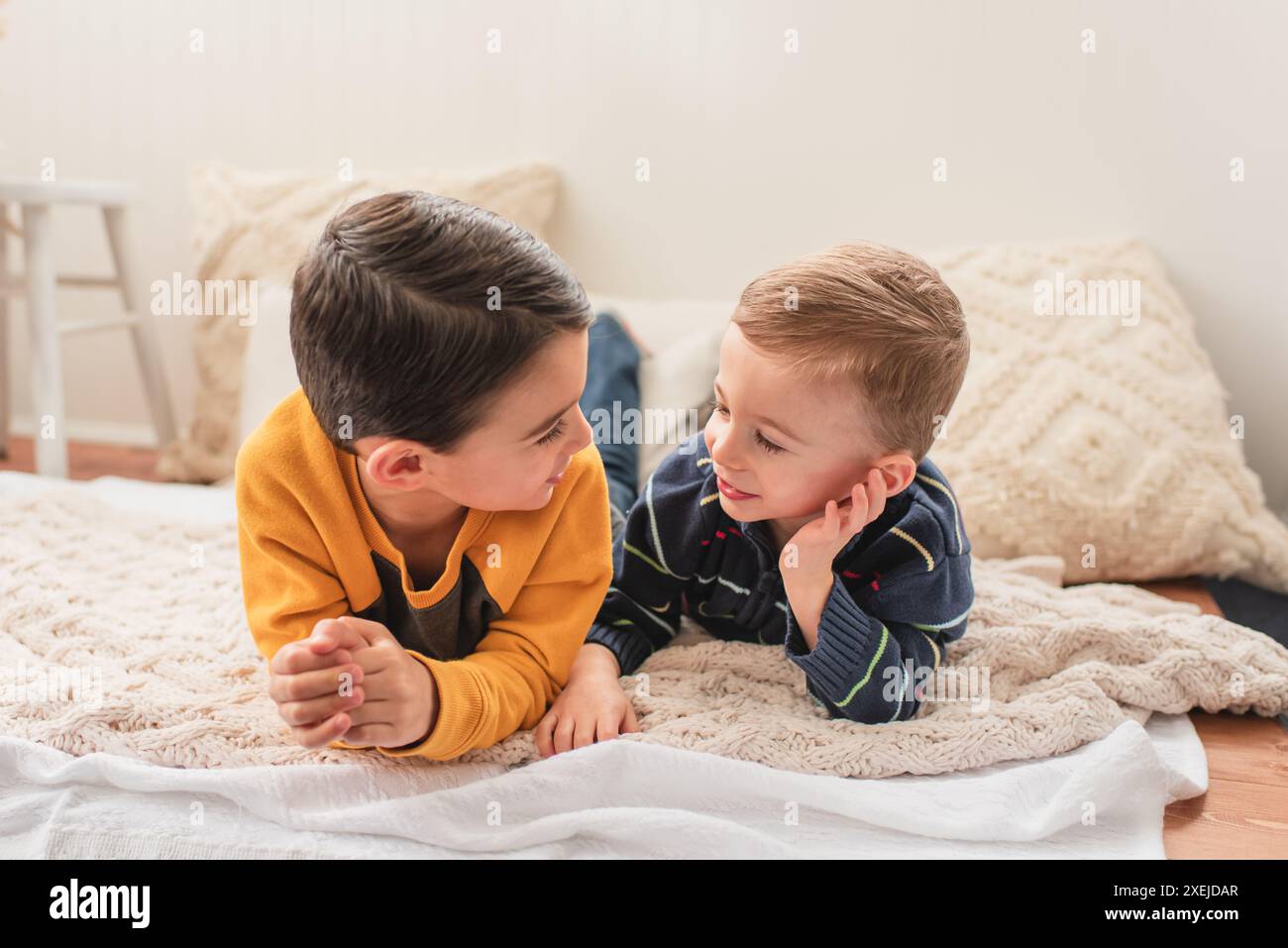 Two smiling brothers lying on a blanket and talking Stock Photo - Alamy