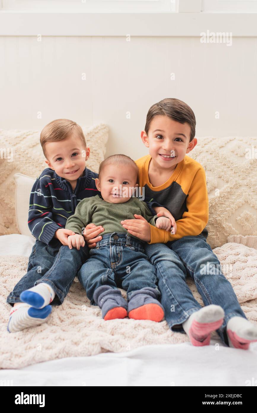 Smiling brothers hugging and smiling while sitting on bed Stock Photo ...