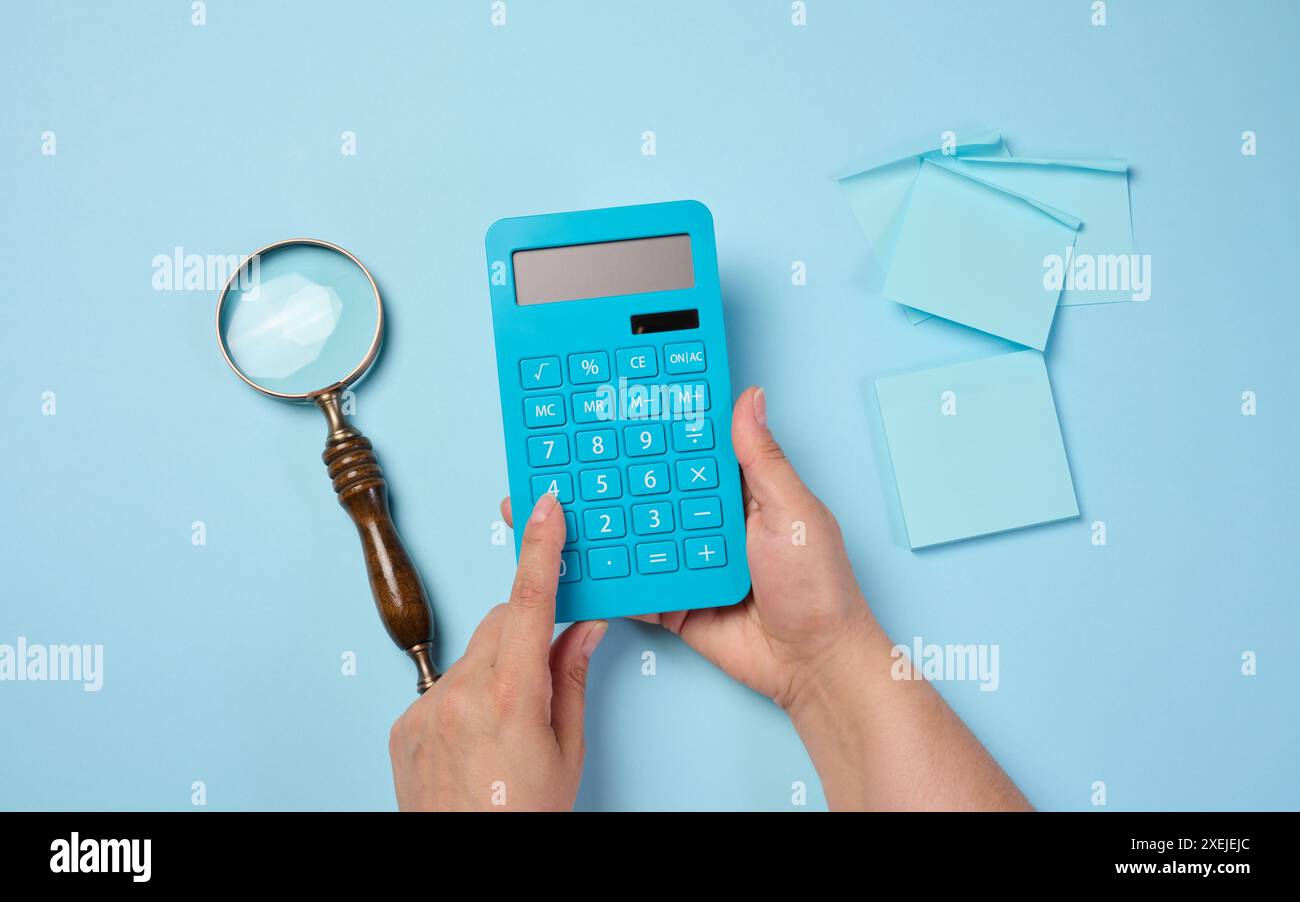 Magnifier and calculator on a blue background, budget calculation. View ...