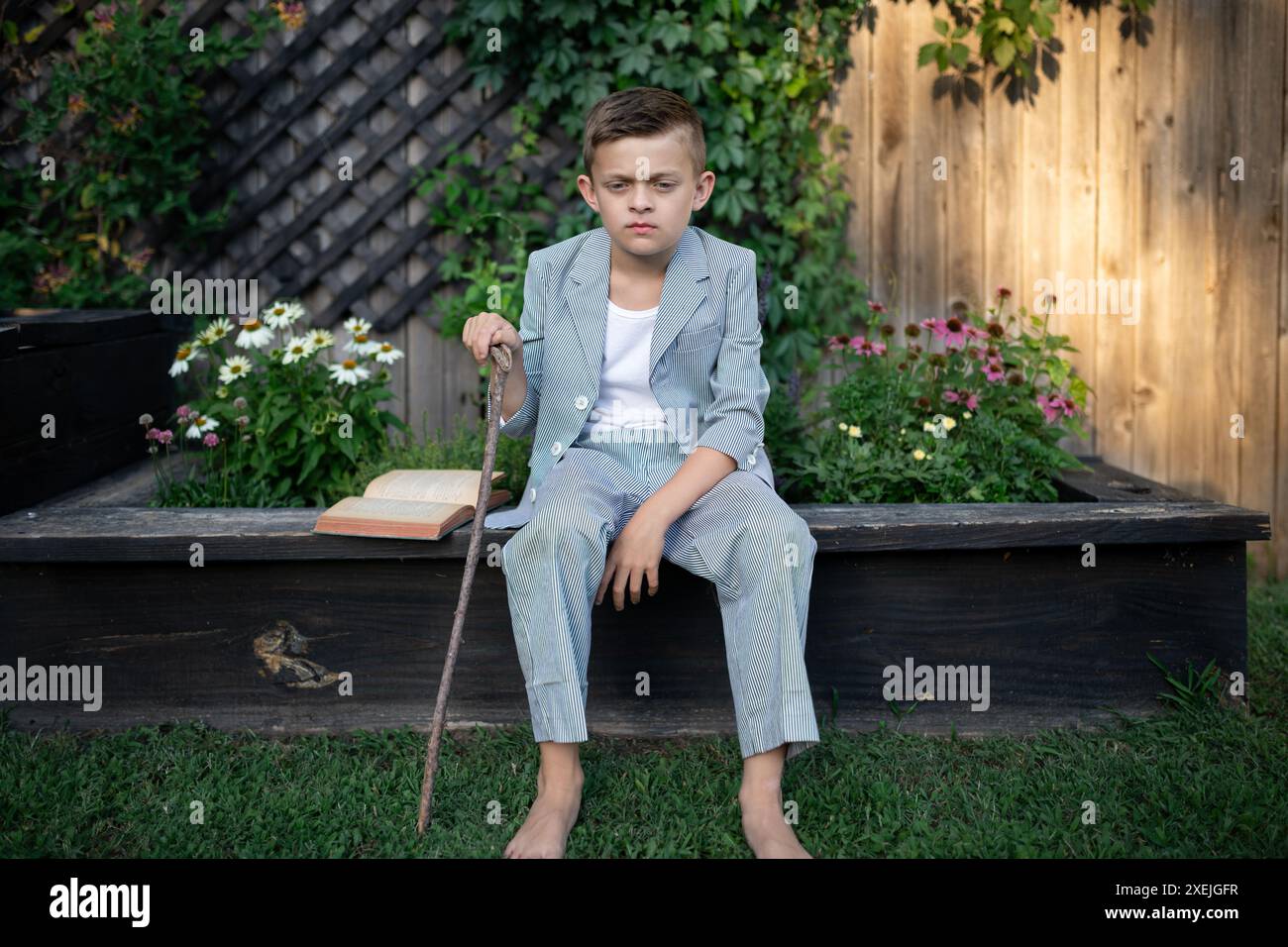 barefoot boy in suit sitting on flower bed with book in golden light Stock Photo - Alamy