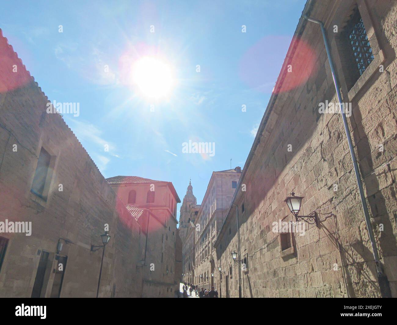 street with sun shining overhead, flanked by old stone buildings Stock ...