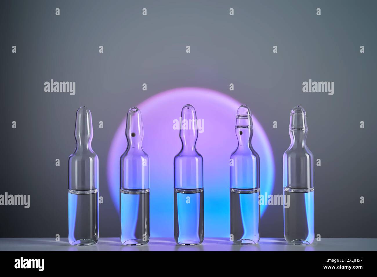 Several ampoules for injection with medicines on a purple background ...