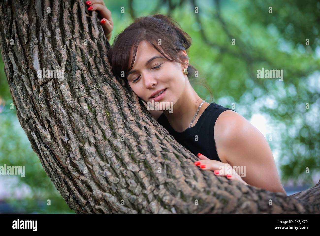 A gorgeous lady poses under a century-old tree, interacting with nature ...
