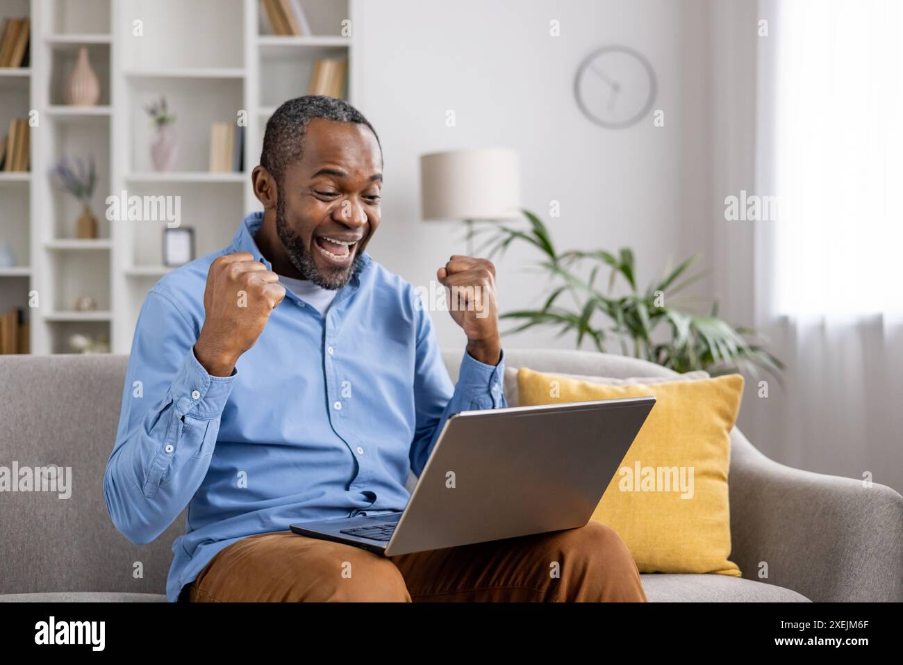 Happy man celebrating success while working from home on laptop. Man ...