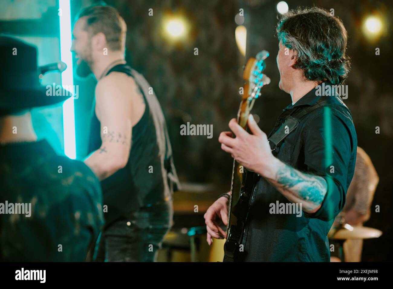 Group of unrecognizable rock musicians enjoying playing song on stage ...