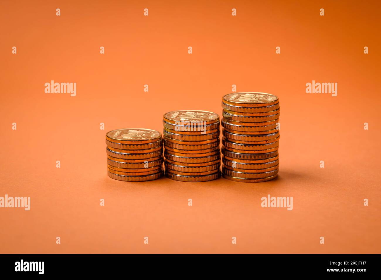 Round metal yellow coins folded in the form of columns on a plain ...